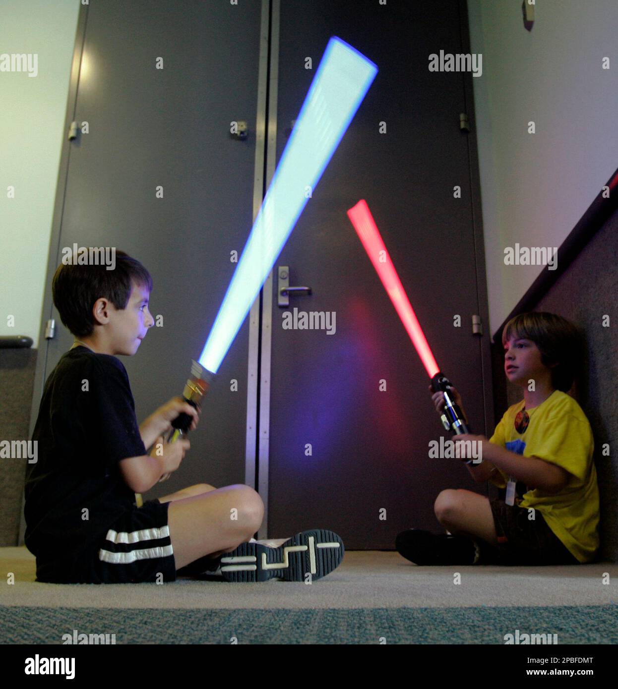 Two boys play with lightsabers as they take a break in an alcove at ...