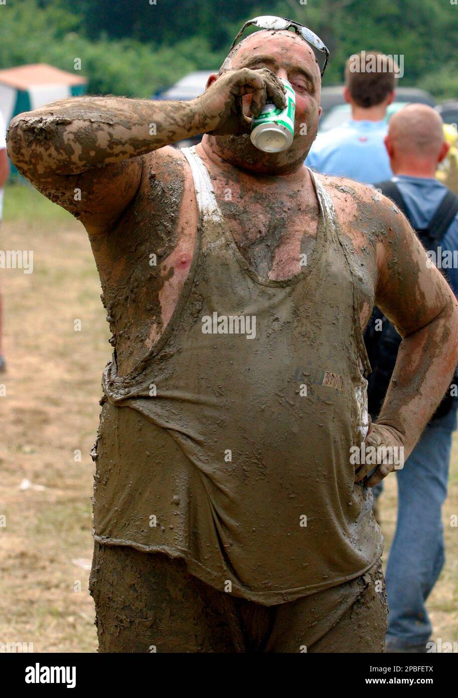 A man covered with mud drinks beer during an off road car festival in ...