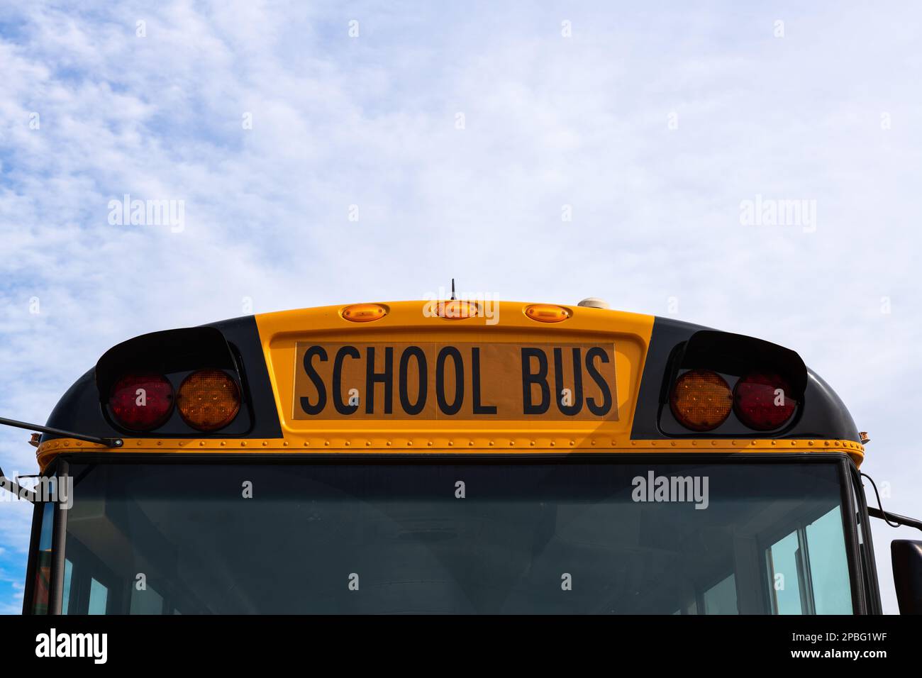 Close-up view of a yellow school bus sign and lights with blue sky ...