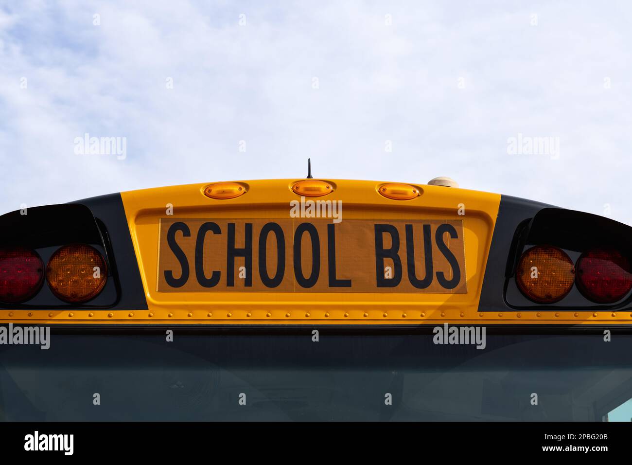 Close-up view of a yellow school bus sign and lights with blue sky ...
