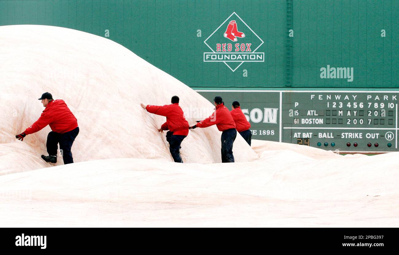 Members of the Fenway Park grounds crew try to hold down the tarp ...