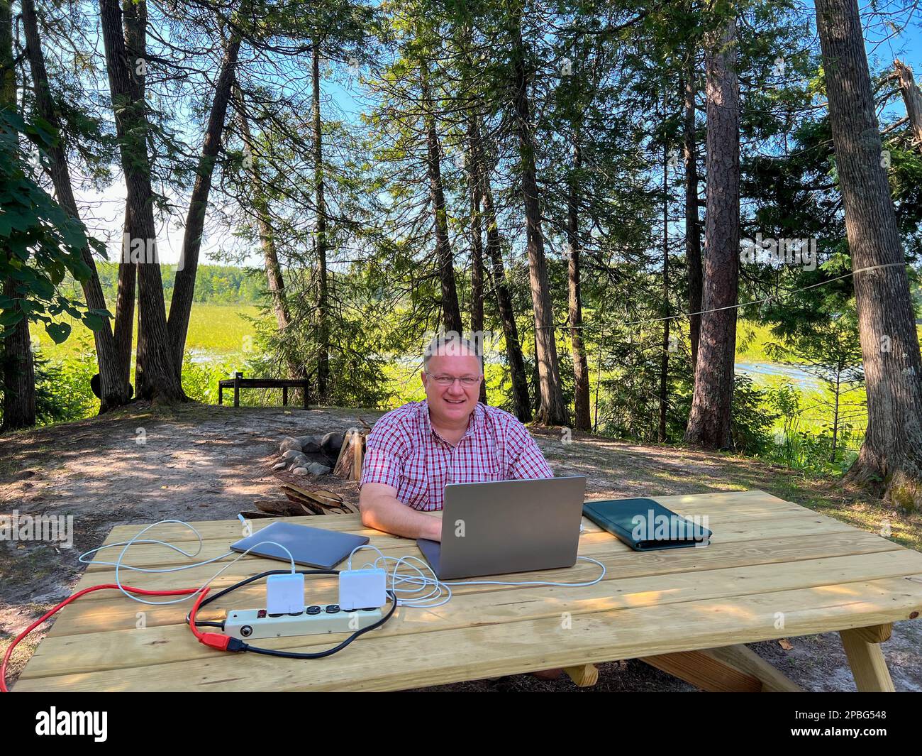 Remote Worker in Pandemic working from picnic table campsite near lake ...