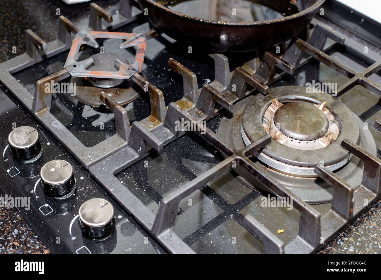 Gas stove with black tempered glass surface with a layer of dust and ...