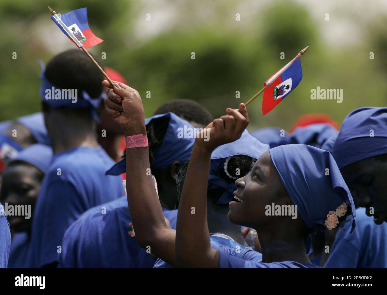 A young woman waves two Haitian flags during a ceremony to mark Flag ...