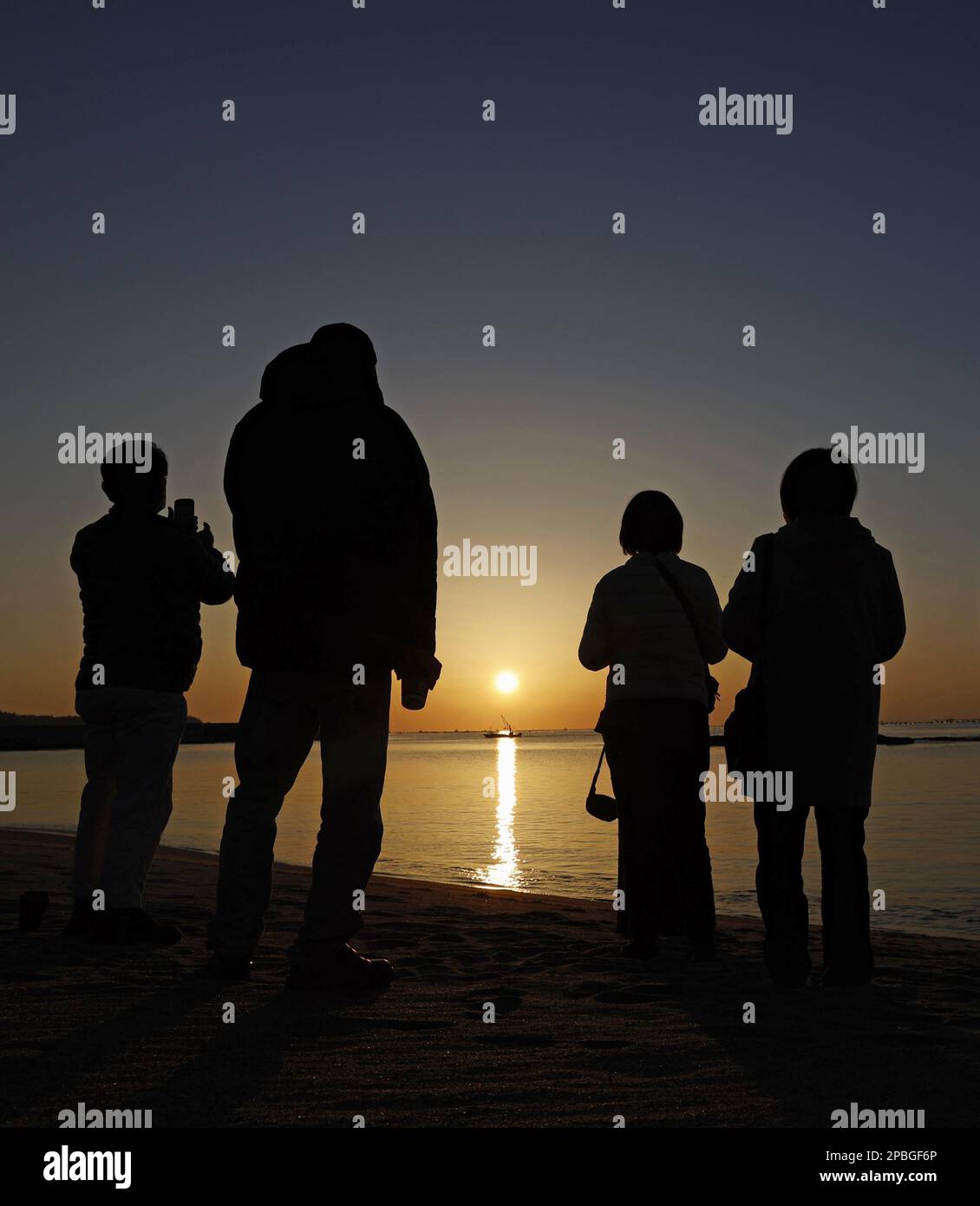 People watch the sunrise from a seashore in the Miyagi Prefecture town ...