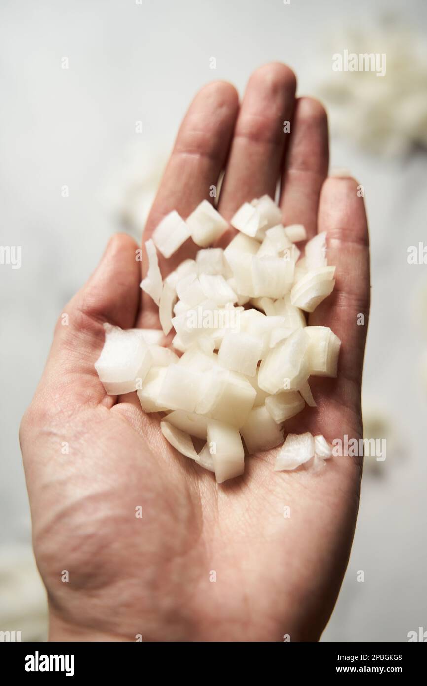 Medium diced onions on mans hand. Photo show how does onion sliced into ...