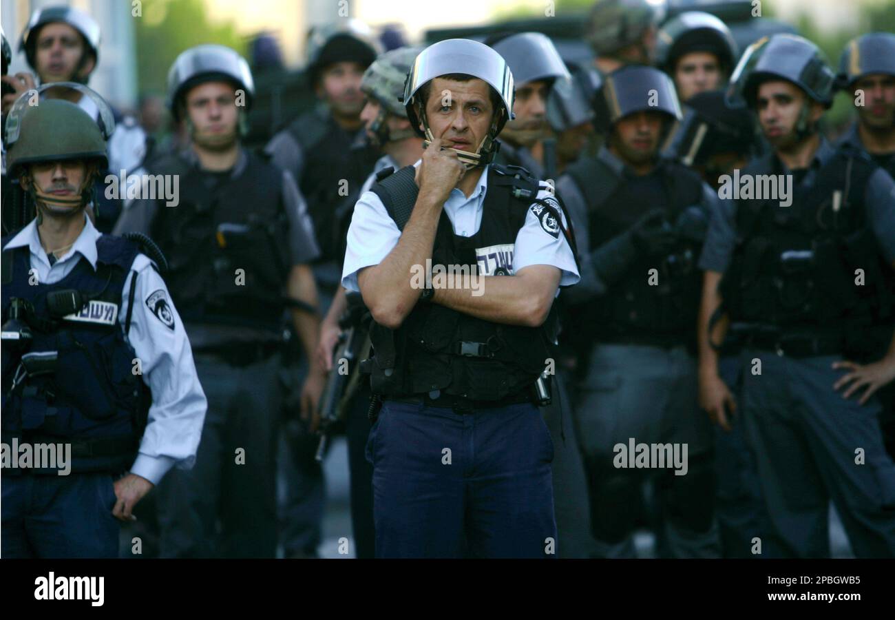 Israeli police officers watch Palestinian mourners carrying the coffin ...