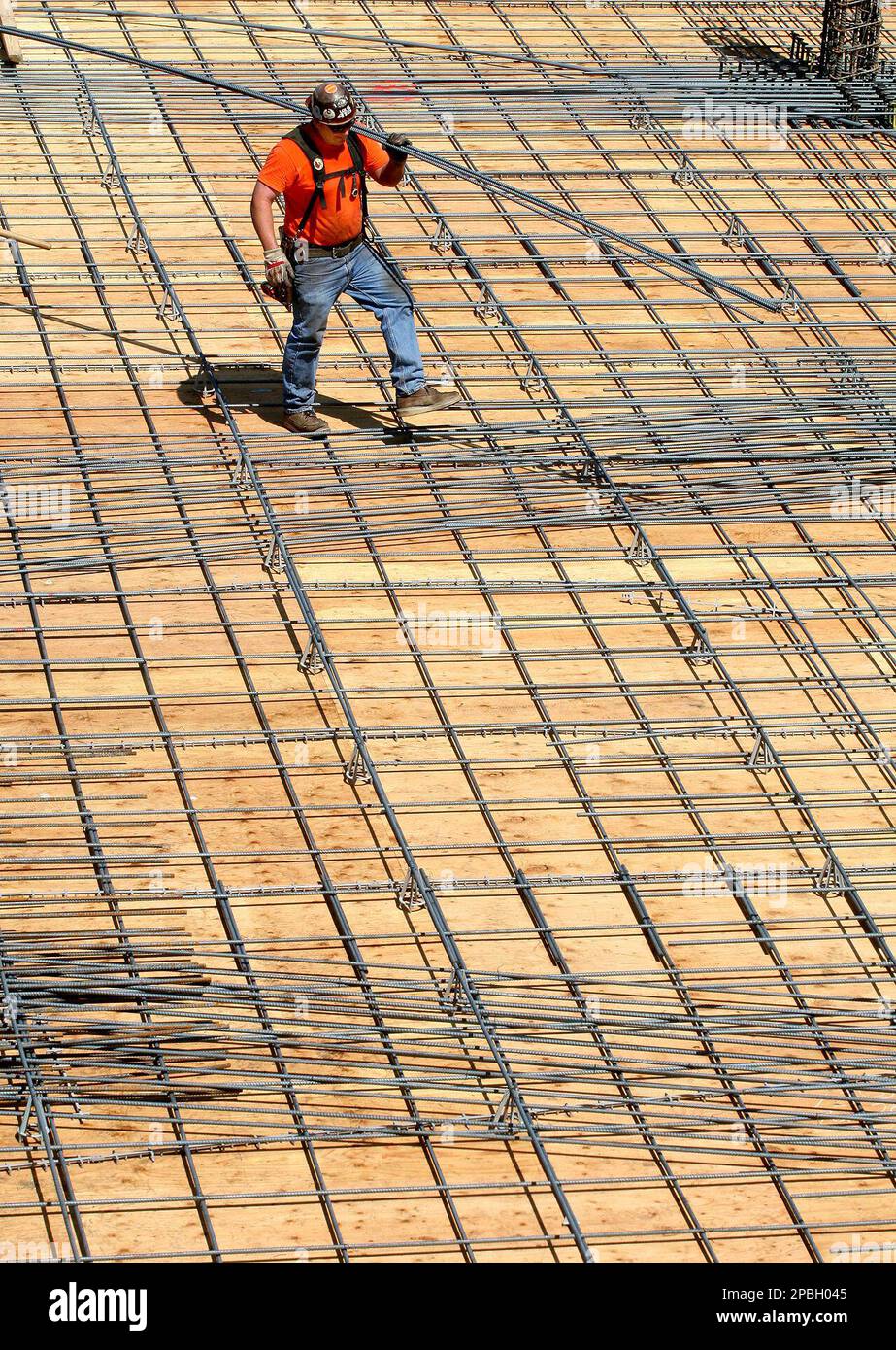 A construction worker for Cascade Steel steps over rebar while carrying ...