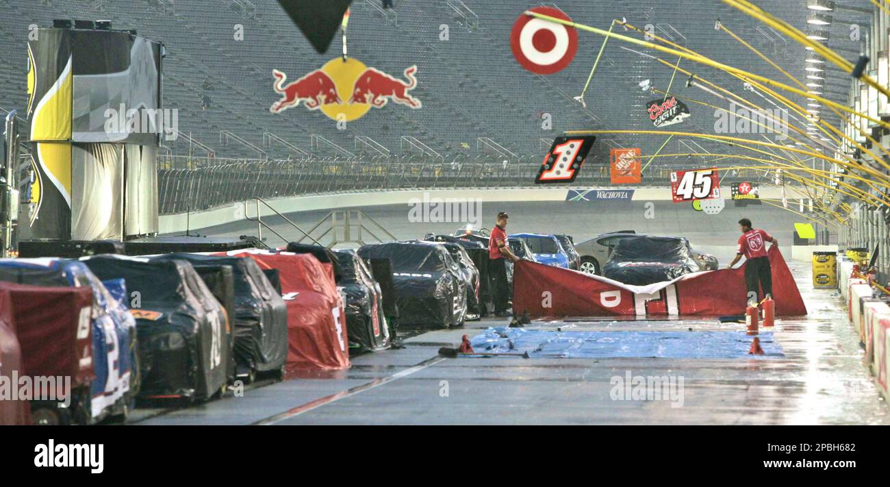 The crew for Kyle Petty lifts a tarp that covered their pit area during ...