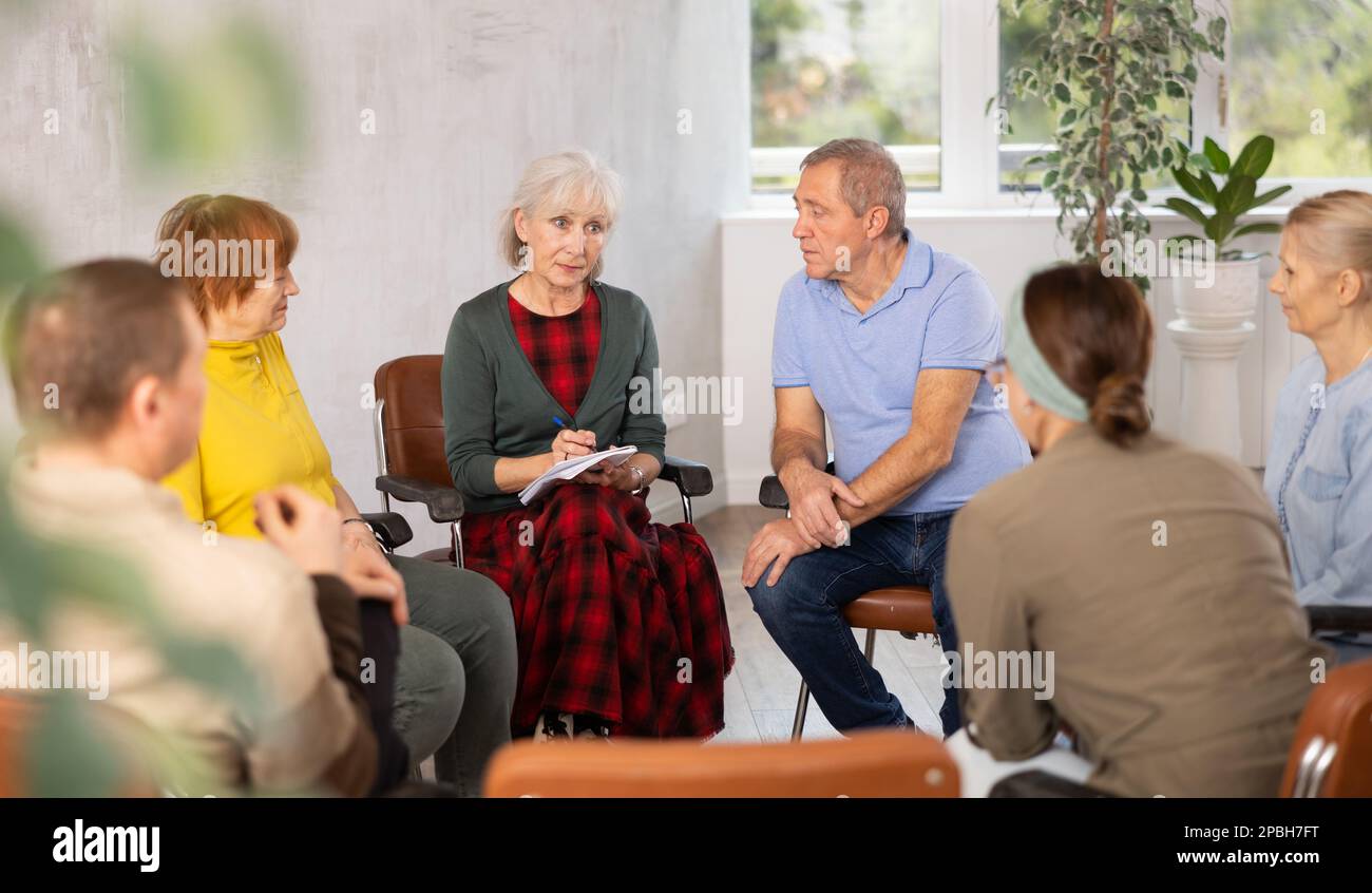 Aged woman conducting language speaking club for older adults Stock ...