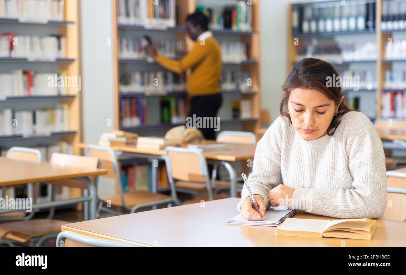 Young adult woman studying in public library Stock Photo - Alamy