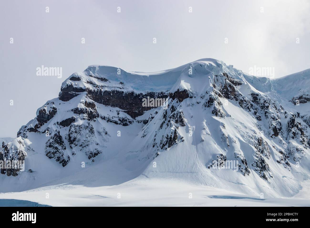 Rugged mountain peak on Antarctic Peninsula. Steep slopes covered with ...
