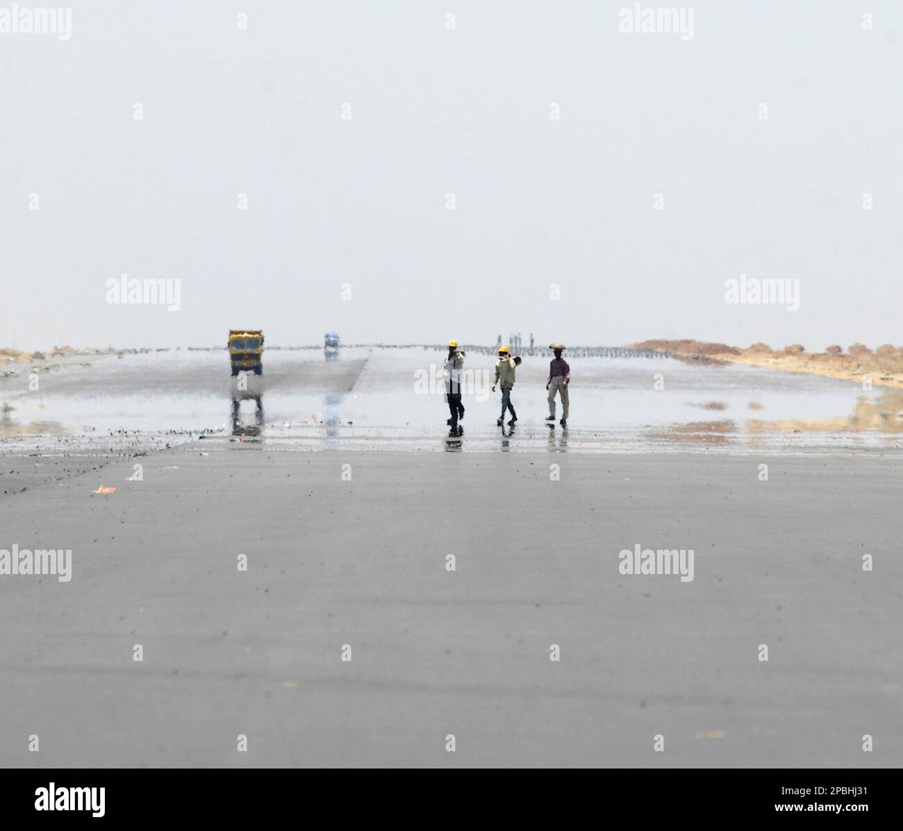 Indian workers walk on the newly laid runway of GMR Hyderabad ...