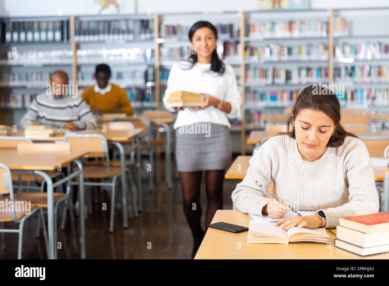 Young adult woman studying in public library Stock Photo - Alamy