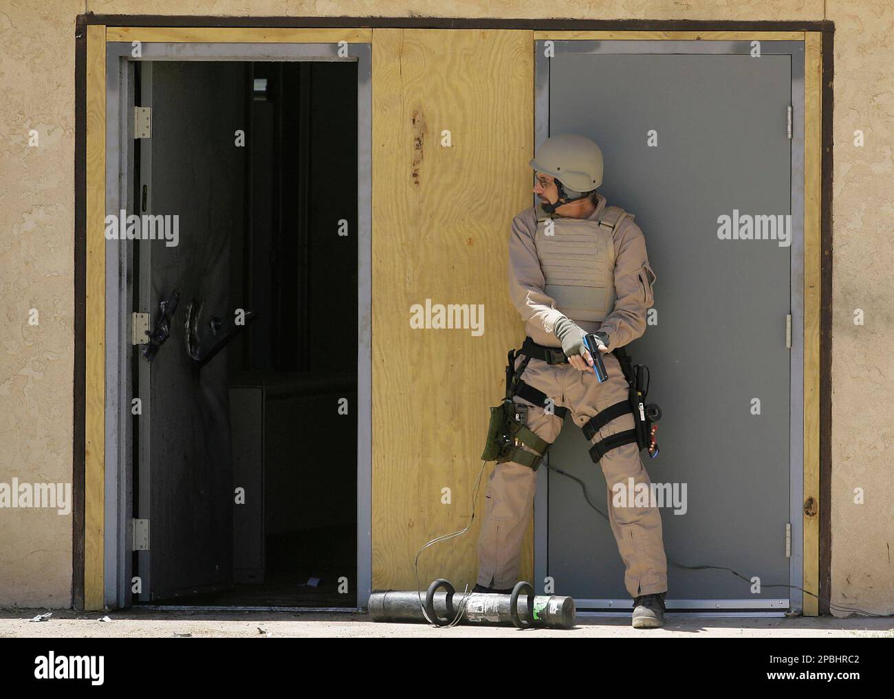 A SWAT team member keeps watch on the exterior of a home during a ...