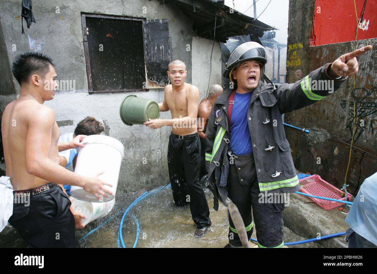 A firefighter calls for water as residents use pail of water as they ...