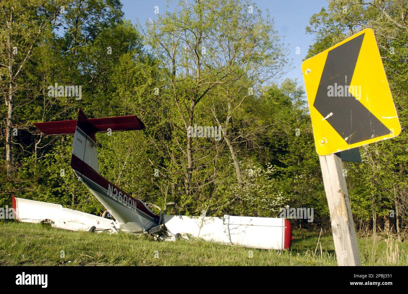 A single-engine airplane sits near an access road after it crashed ...