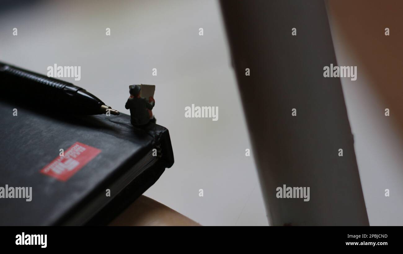 a view of miniature figure reading a newspaper on a book Stock Photo ...
