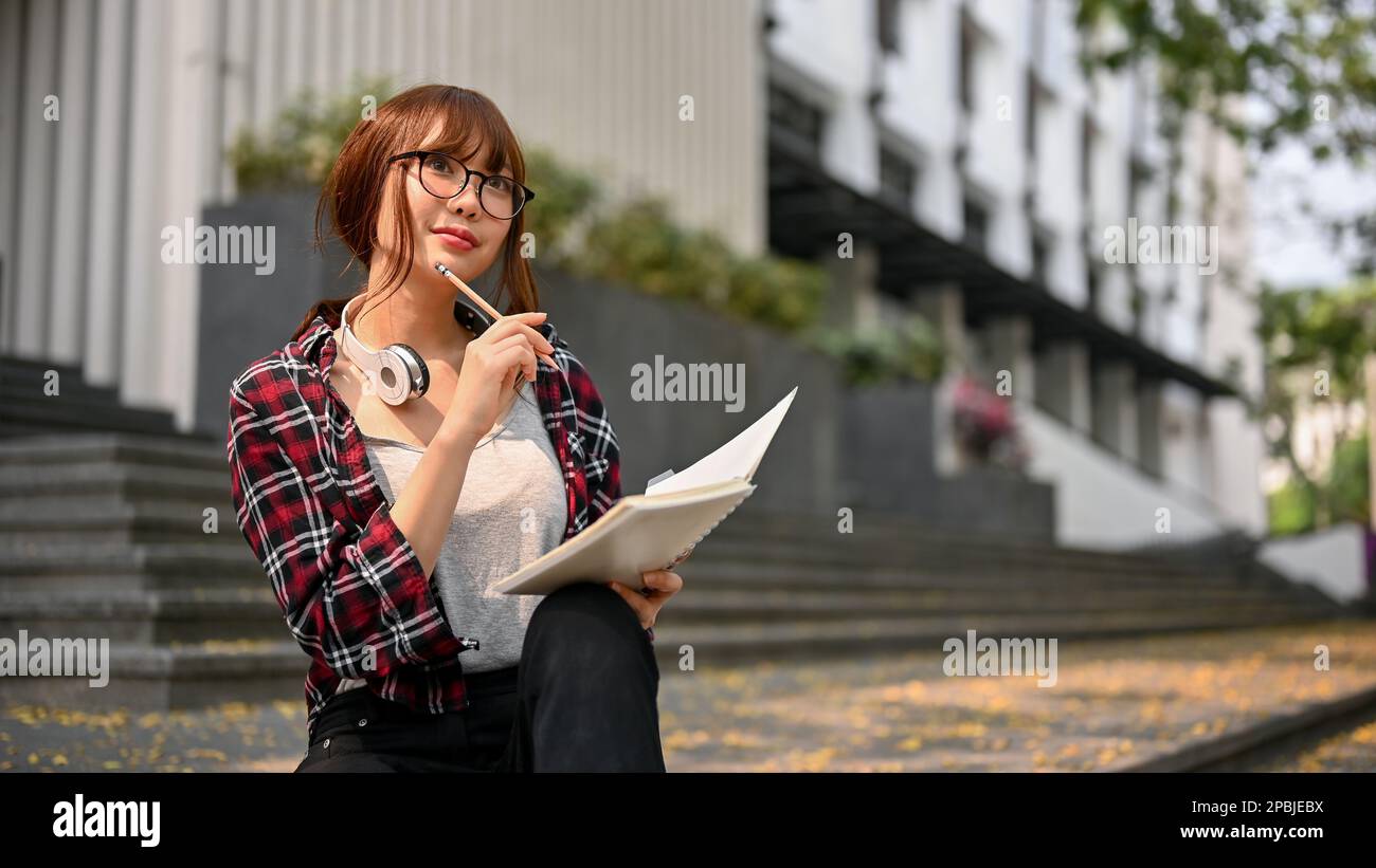 Smart and inspired young Asian female college student in casual clothes ...