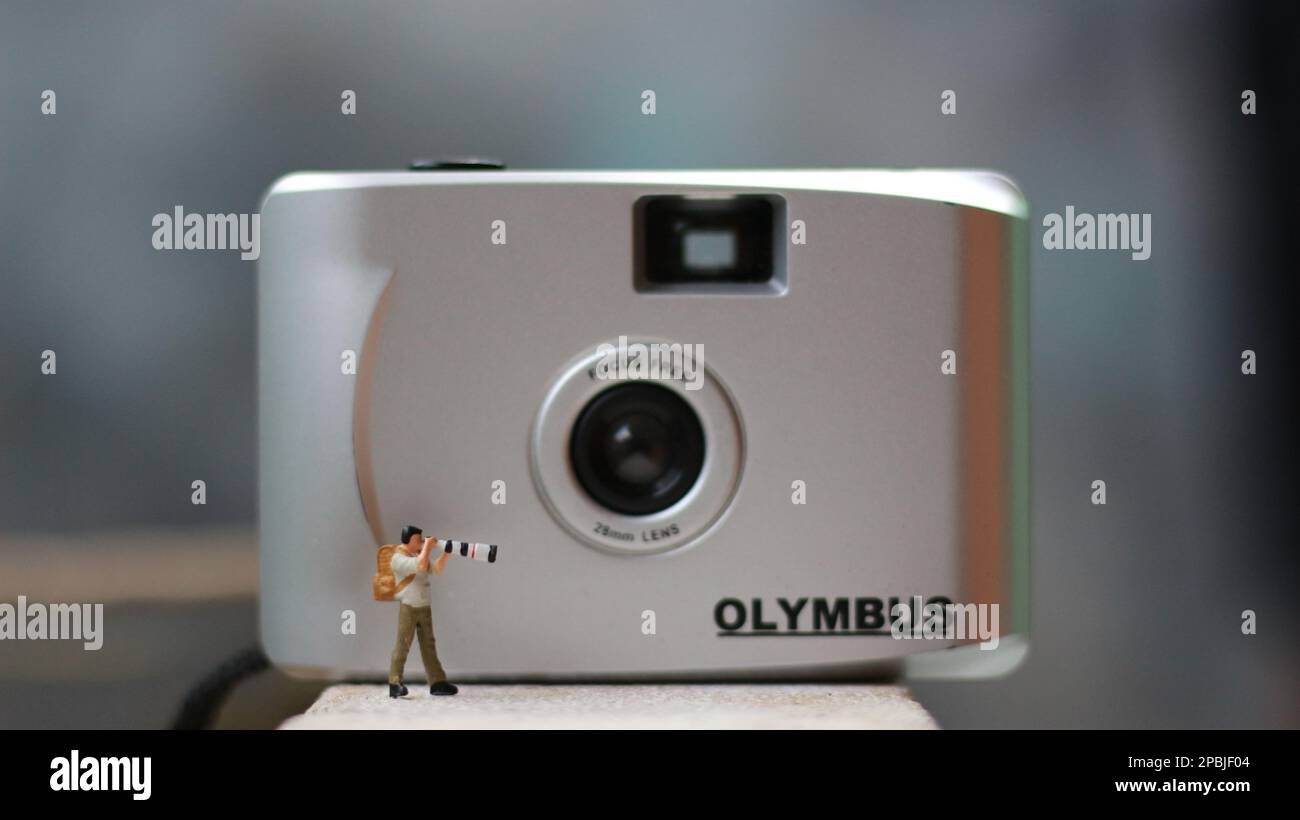 a miniature figure taking picture with a camera against a real camera ...
