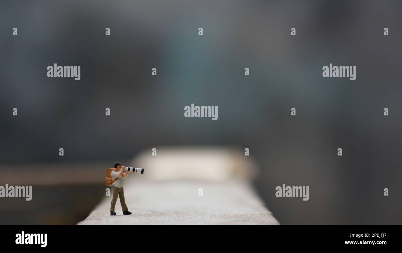 a miniature figure taking picture with a camera against a real camera ...