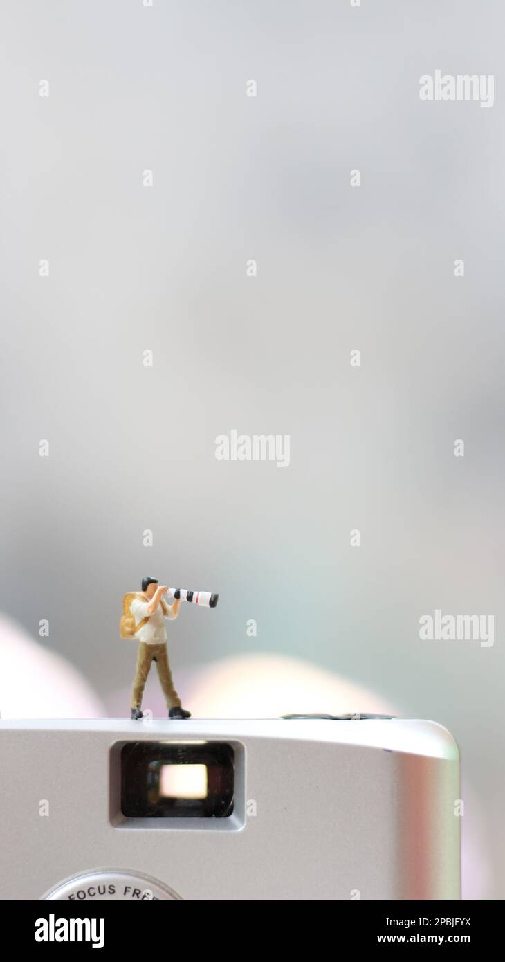 a miniature figure taking picture with a camera against a real camera ...