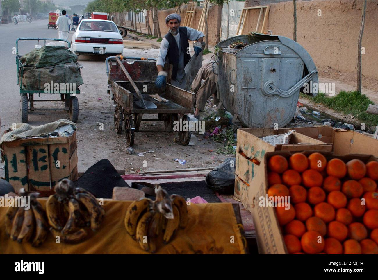 An Afghan man puts garbage into a trash can in Herat province ...
