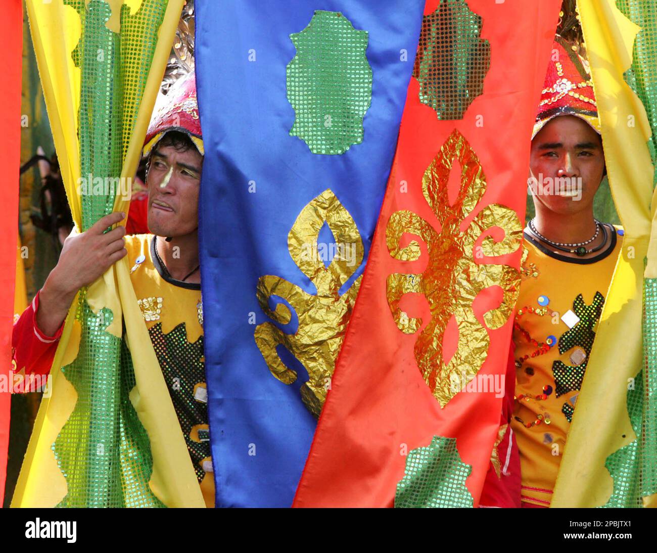 Two Filipino performers peek thru their colorful streamers before the ...