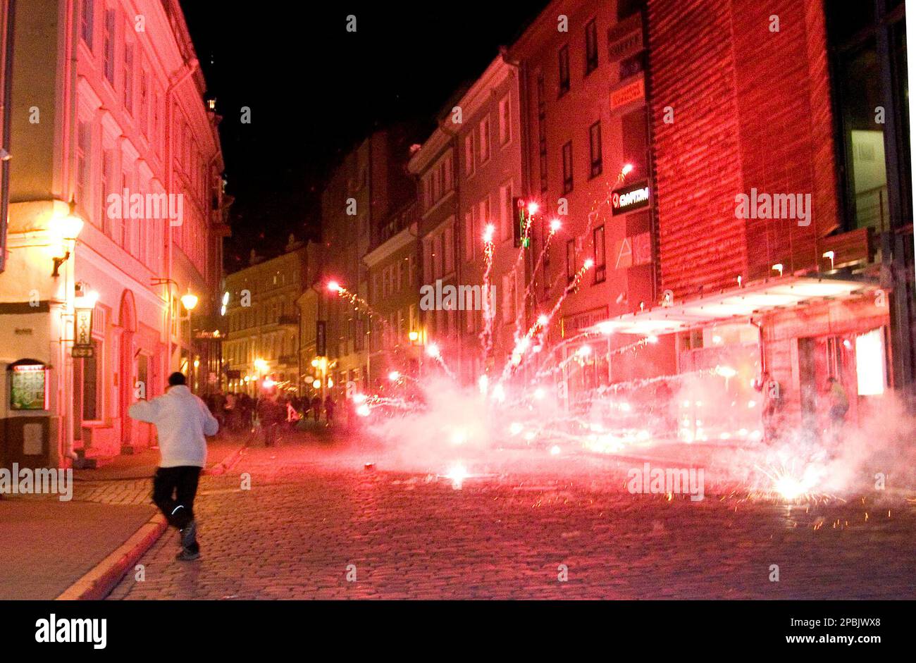 A man runs by exploding flares launched by rebels on a street of ...