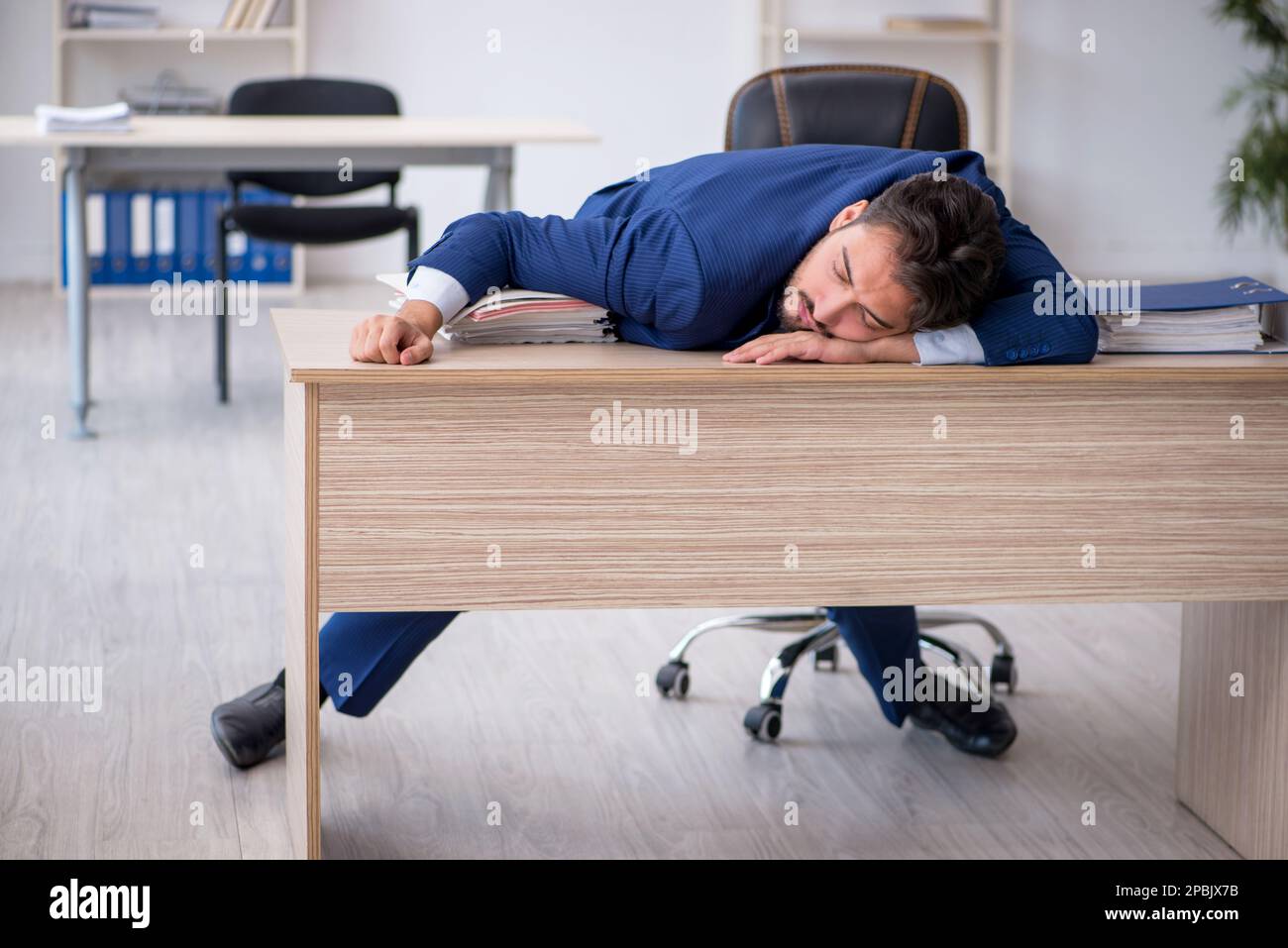 Young businessman employee extremely tired at workplace Stock Photo - Alamy