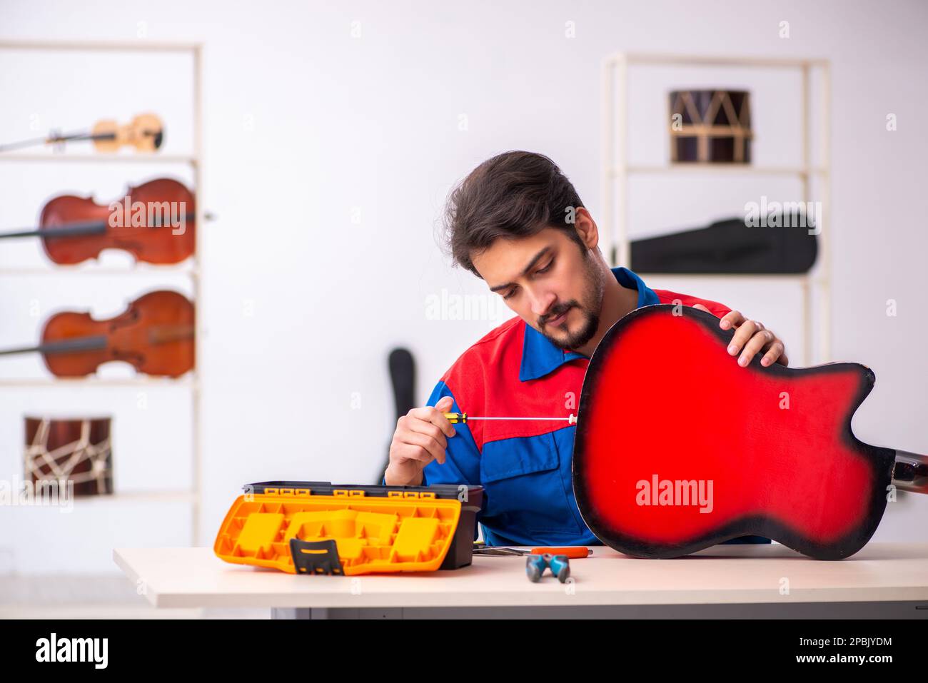 Young repairman repairing musical instruments at workplace Stock Photo ...