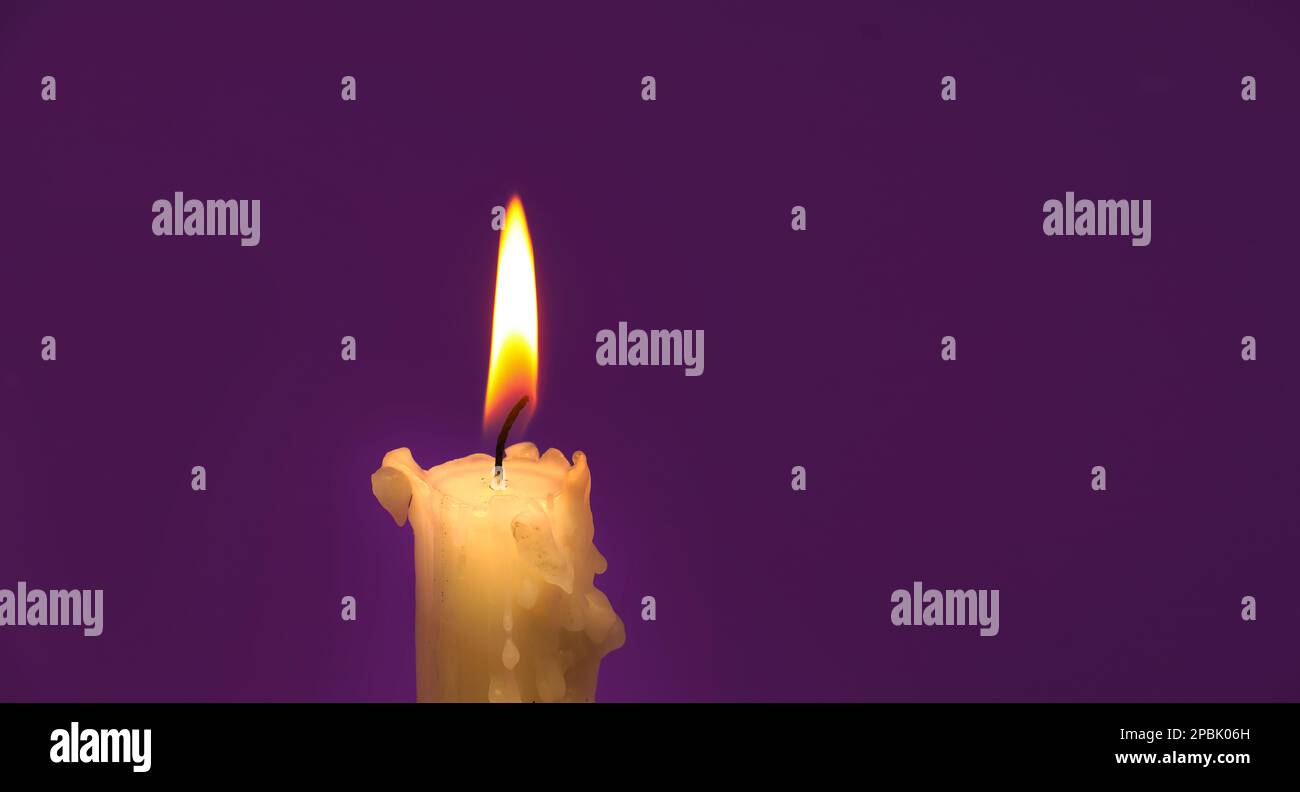 Single burning wax candle over purple background. Banner size image ...