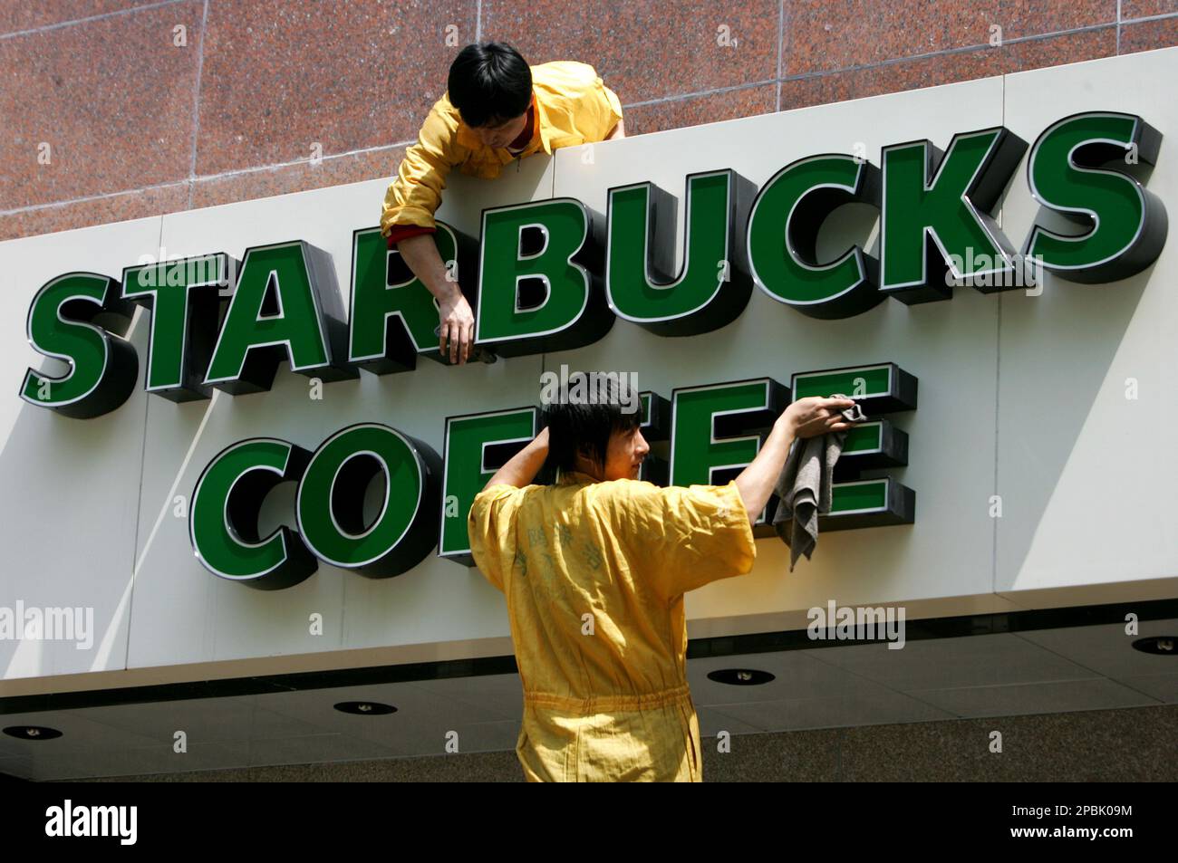 Workers clean the sign outside one of many Starbucks outlets in Beijing ...
