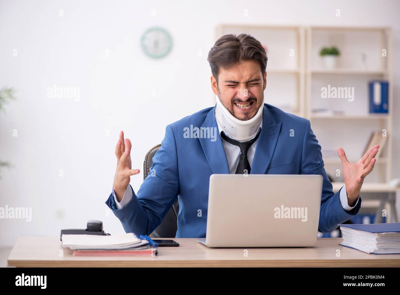 Young neck injured businessman employee at workplace Stock Photo - Alamy