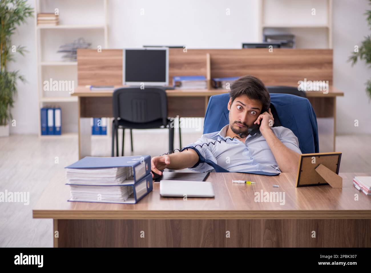 Young male drug addicted employee in the office Stock Photo - Alamy