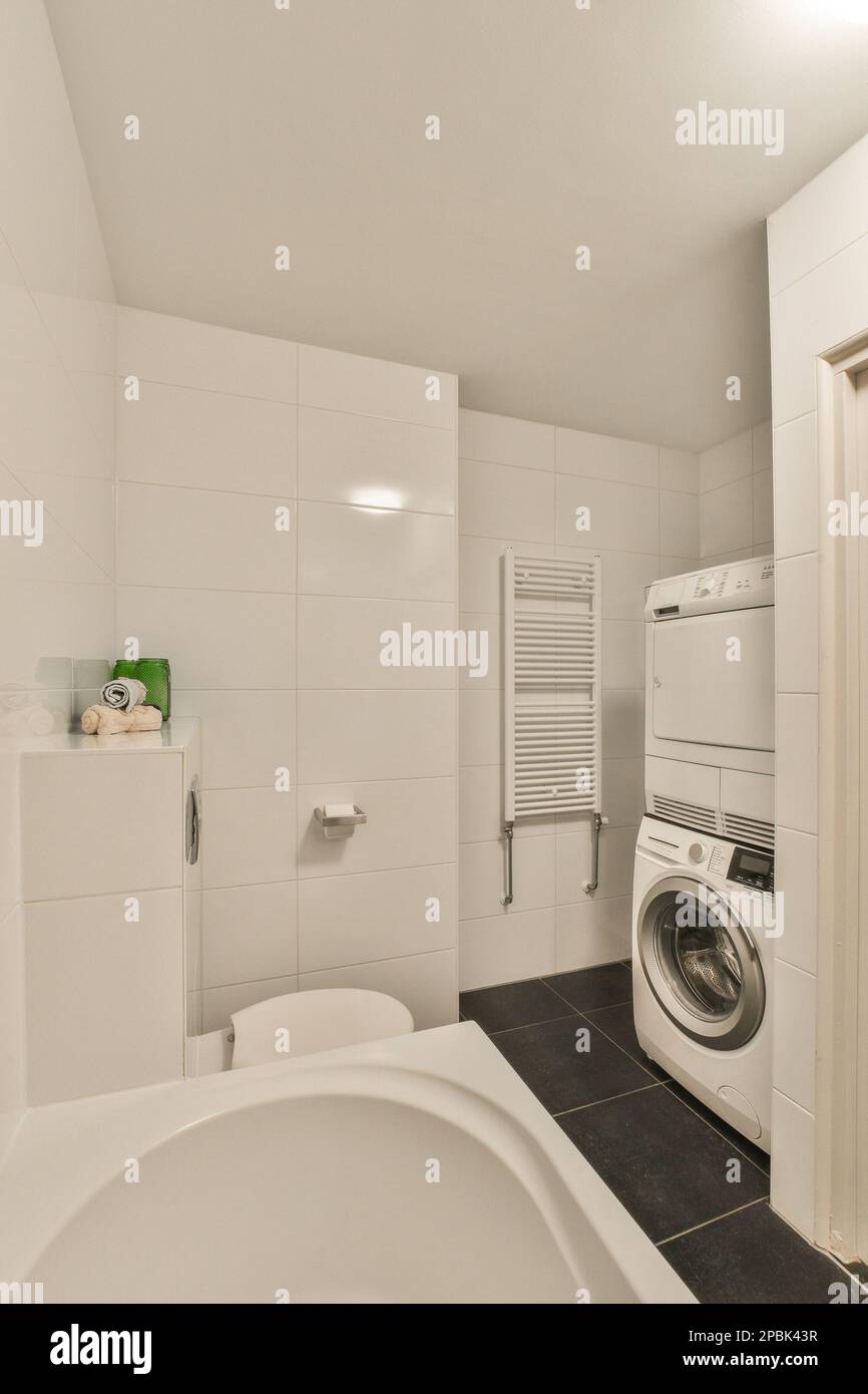 a laundry room with a washer and dryer in the corner, next to a bathtub ...