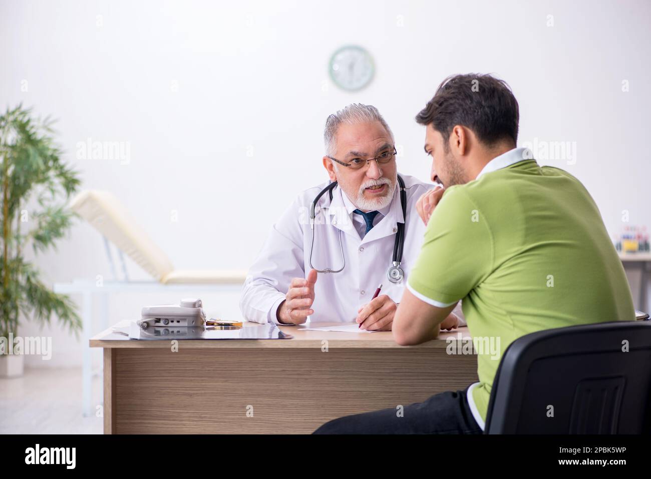 Young man visiting old doctor Stock Photo - Alamy