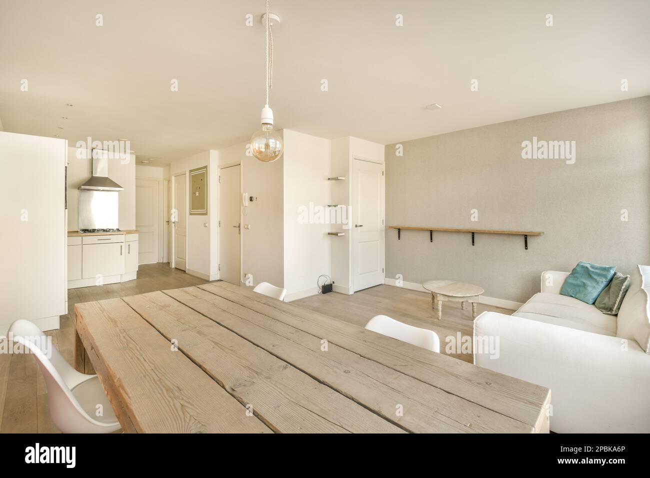 a kitchen and dining area in a room with white walls, wood flooring and ...