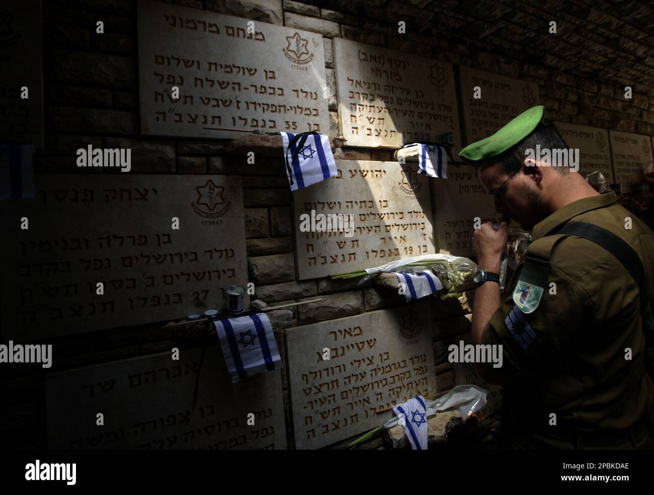 An Israeli soldier looks at memorial stones for fallen soldiers during ...
