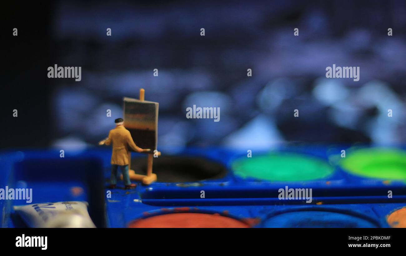 a miniature figure of a painter painting a landscape on watercolors ...