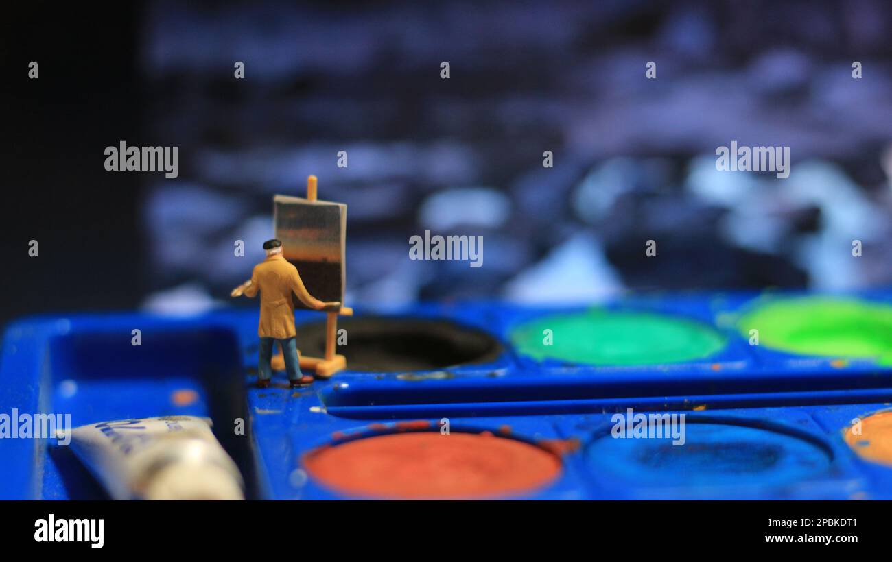 a miniature figure of a painter painting a landscape on watercolors ...