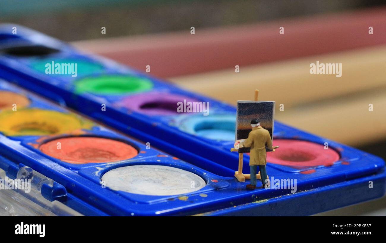 a miniature figure of a painter painting a landscape on watercolors ...