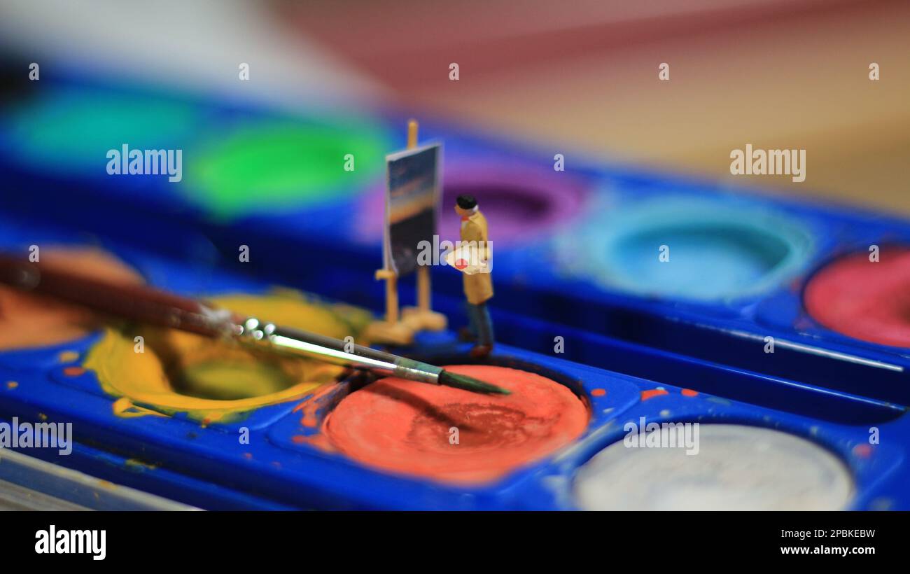 a miniature figure of a painter painting a landscape on watercolors ...