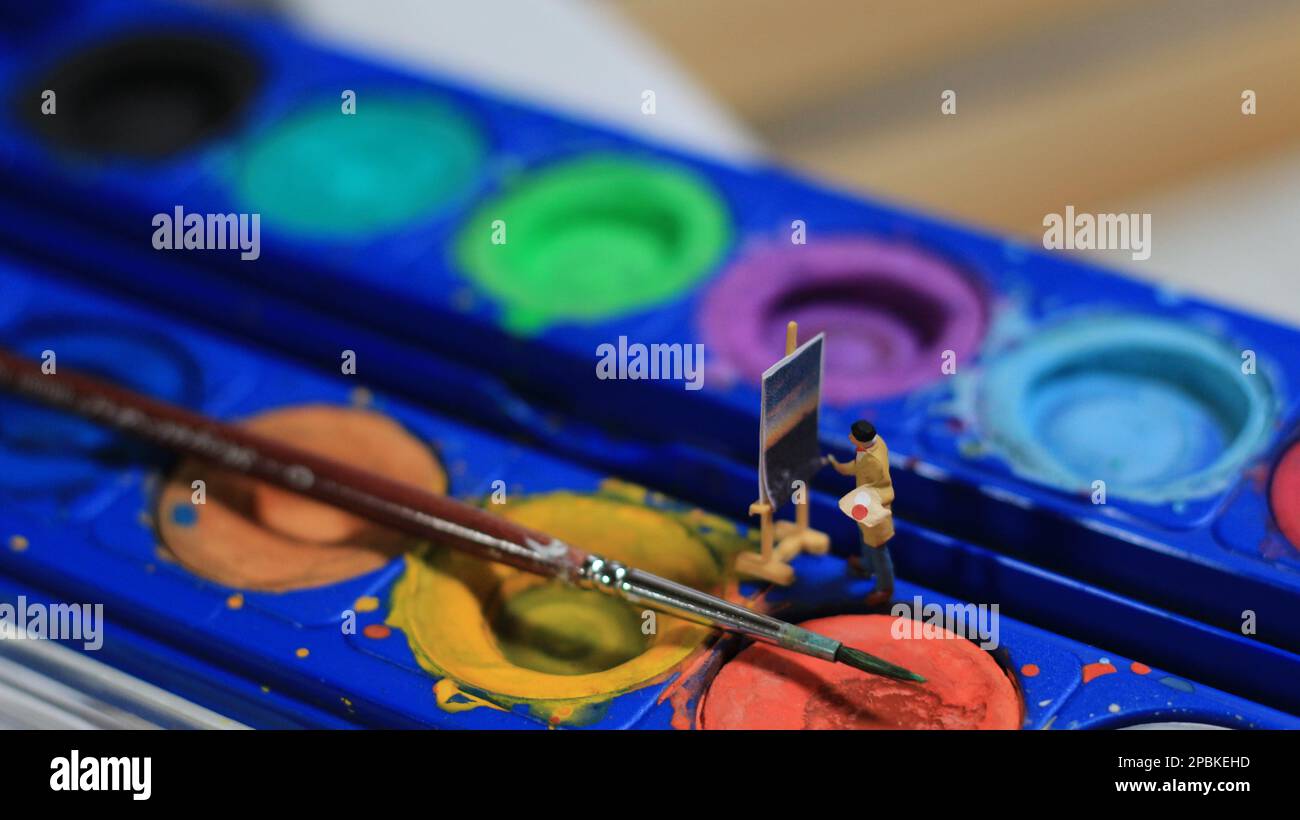 a miniature figure of a painter painting a landscape on watercolors ...