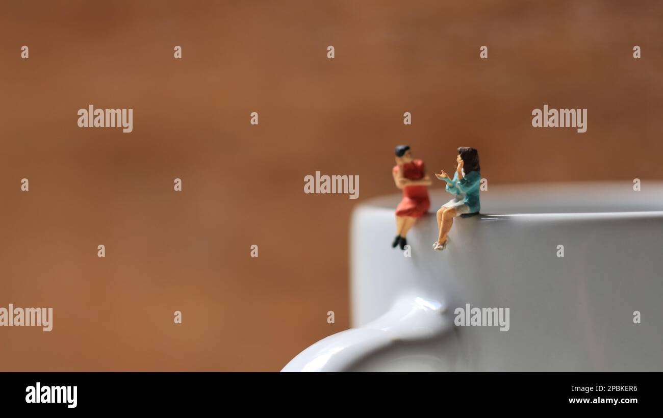 Miniature figures of 2 women talking over glasses. discussion concept ...