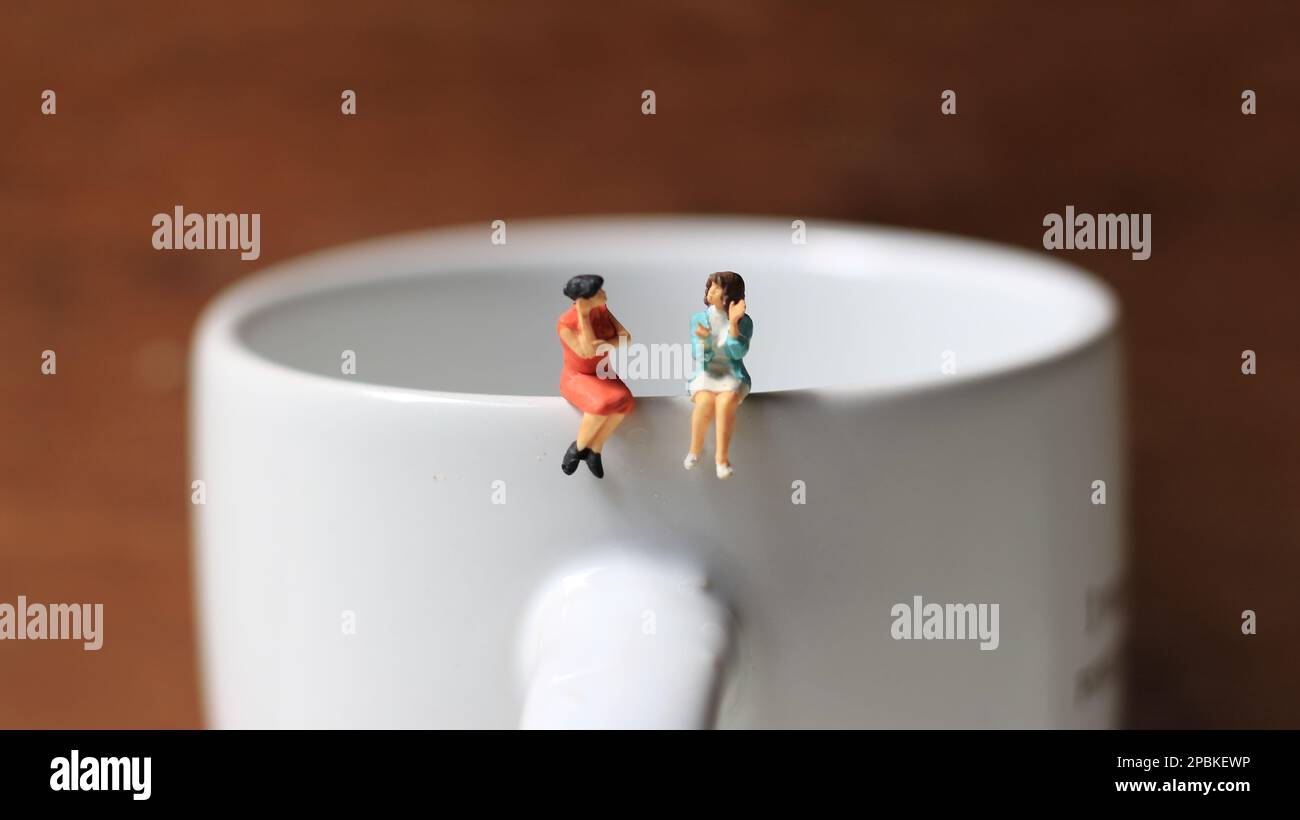 Miniature figures of 2 women talking over glasses. discussion concept ...