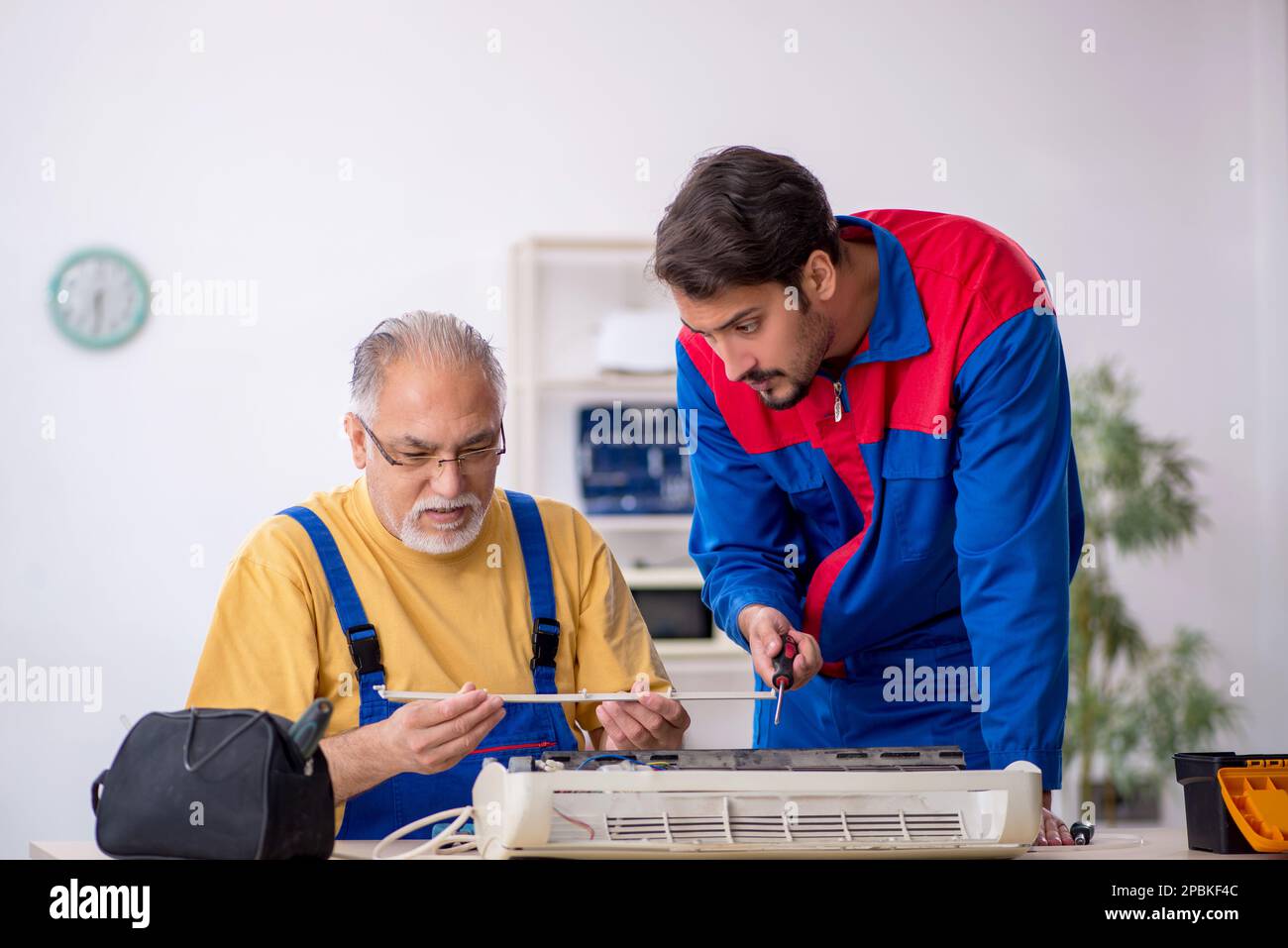Two repairmen repairing air-conditioner at workshop Stock Photo - Alamy