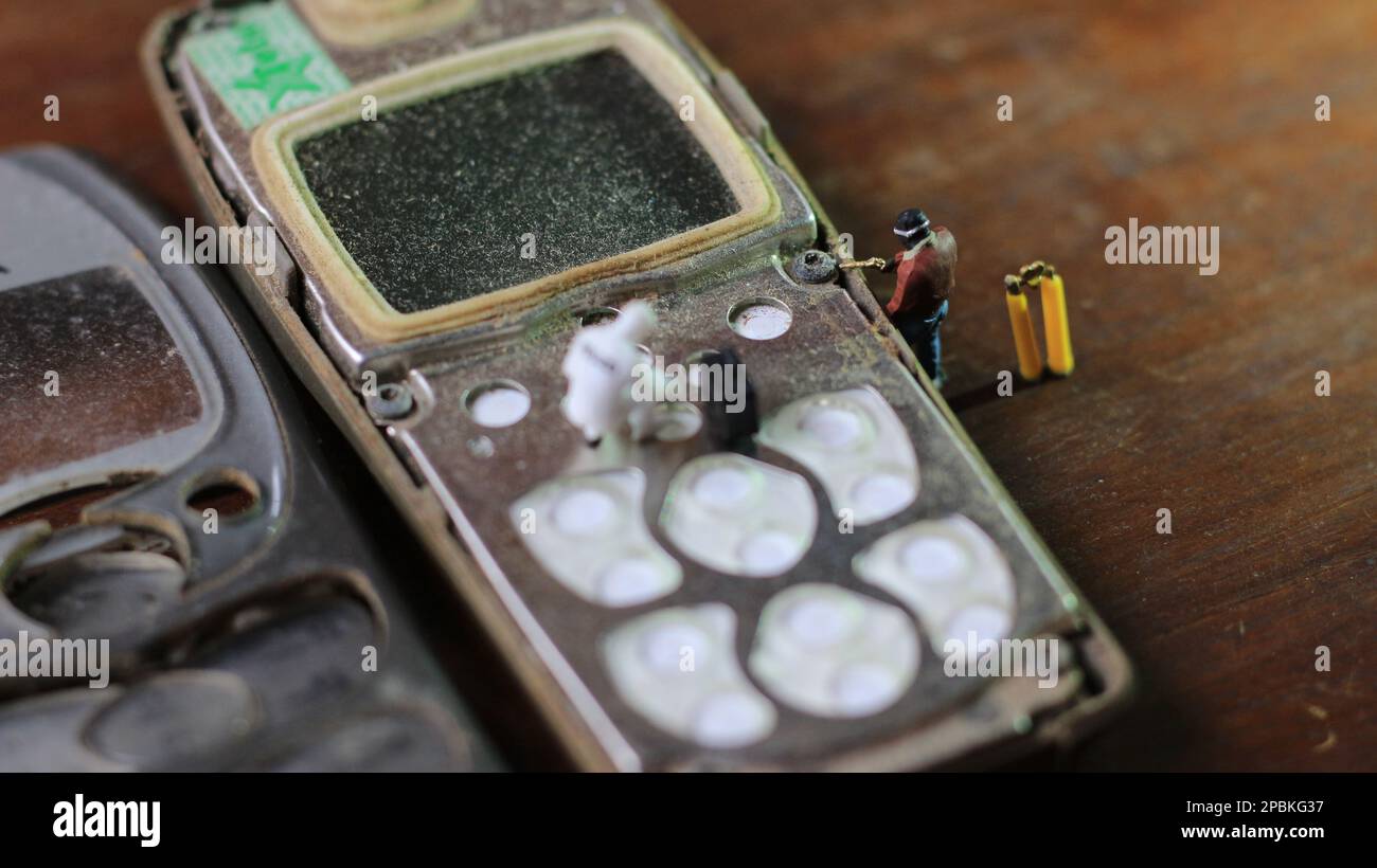 miniature figure of a technician repairing an old broken cell phone ...