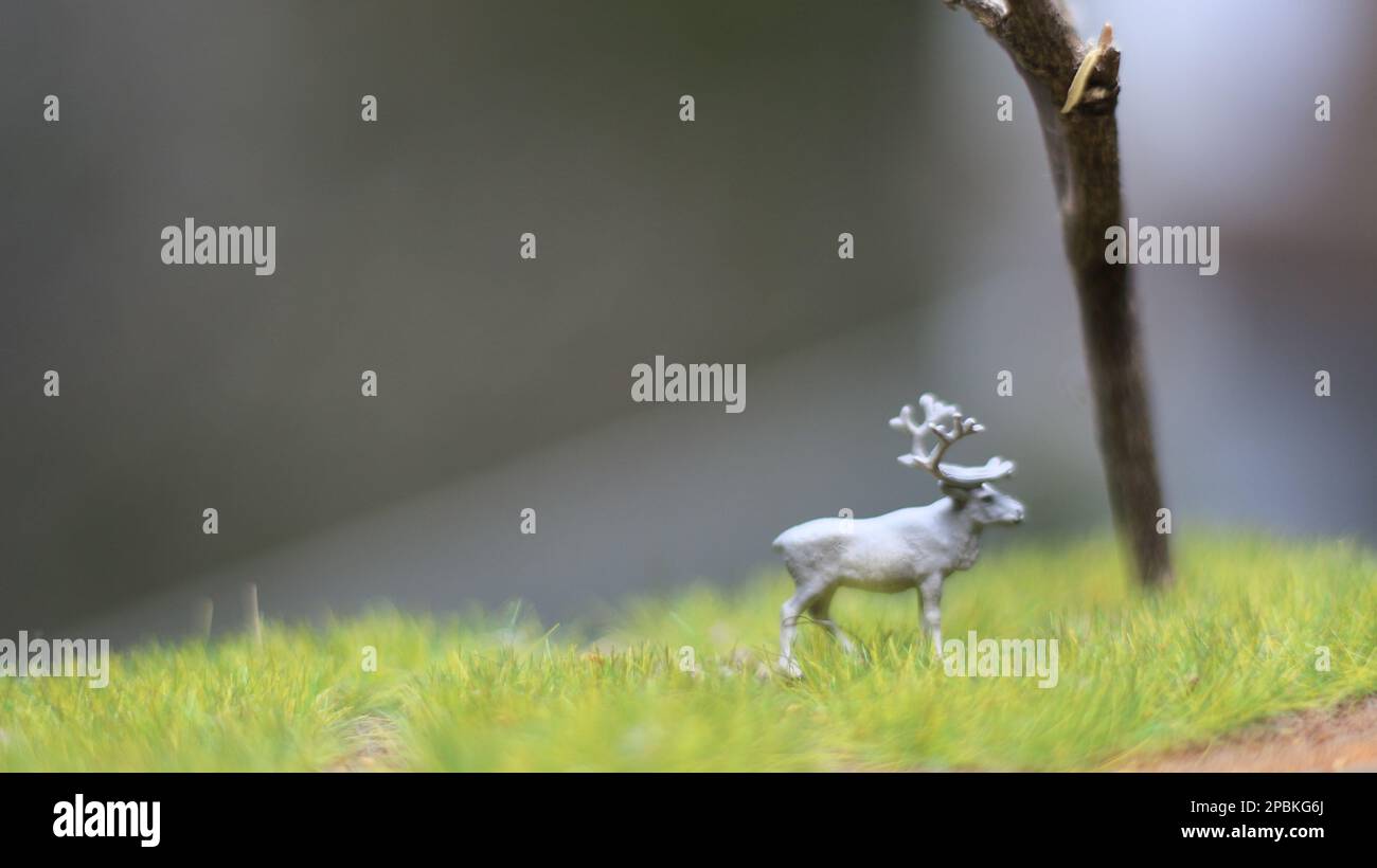 miniature figure of a moose eating. a meadow and tree diorama. concept ...
