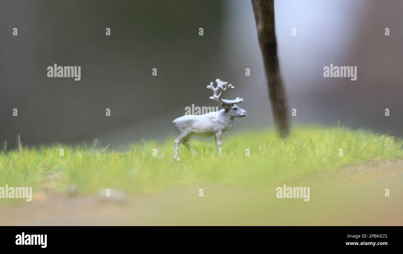 miniature figure of a moose eating. a meadow and tree diorama. concept ...